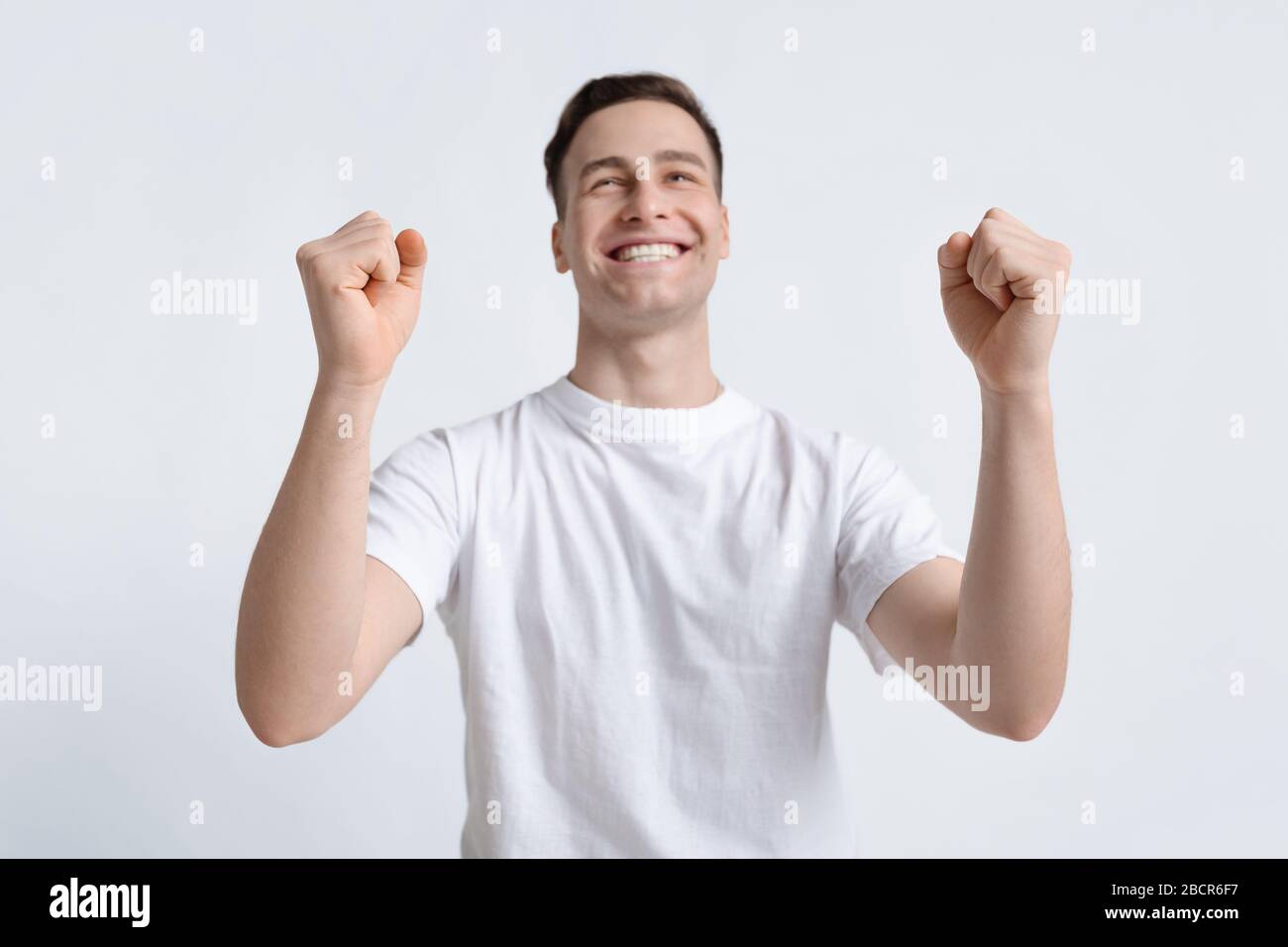 Success concept. Happy guy raises his fists up Stock Photo - Alamy