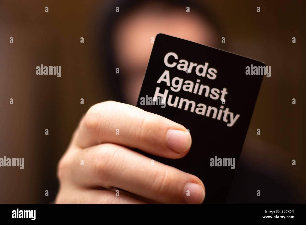 Blurred man in the background holding a black cards against humanity ...