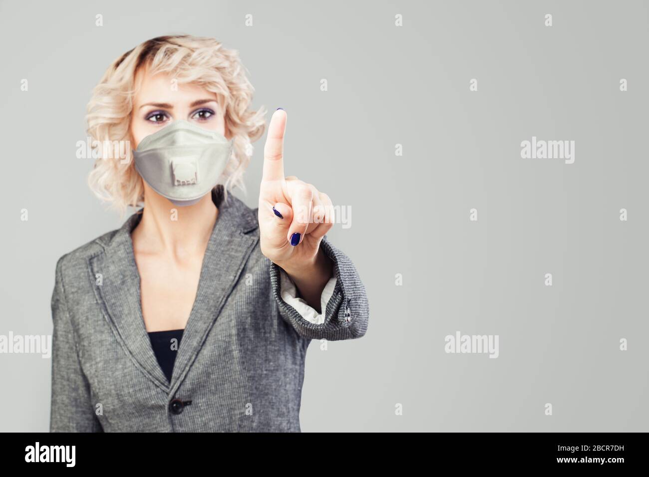 Pointing finger. Woman in face mask pushing on white background Stock ...