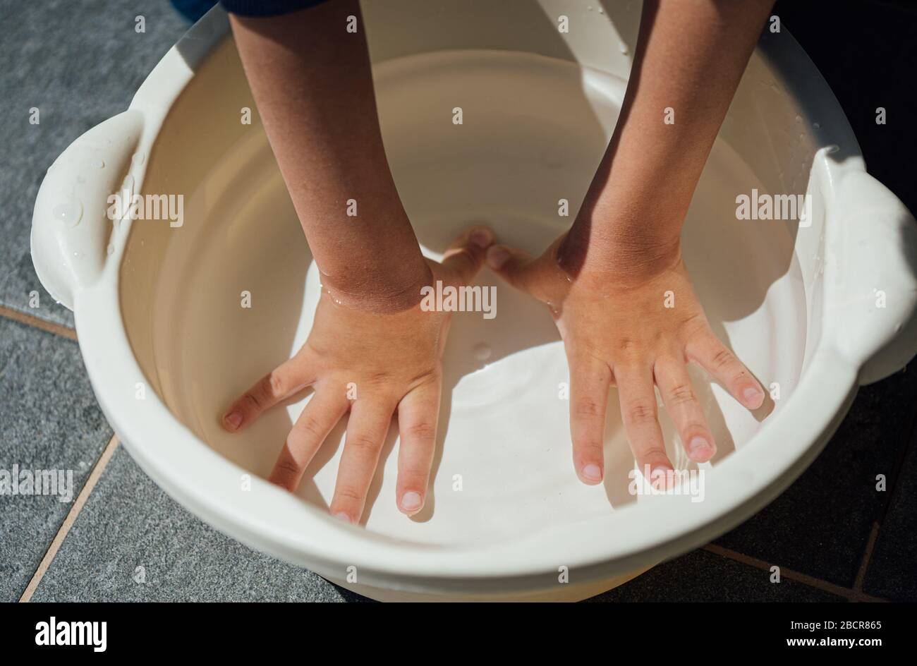 Boy submerging and washing his hands inside a basin with water Stock ...