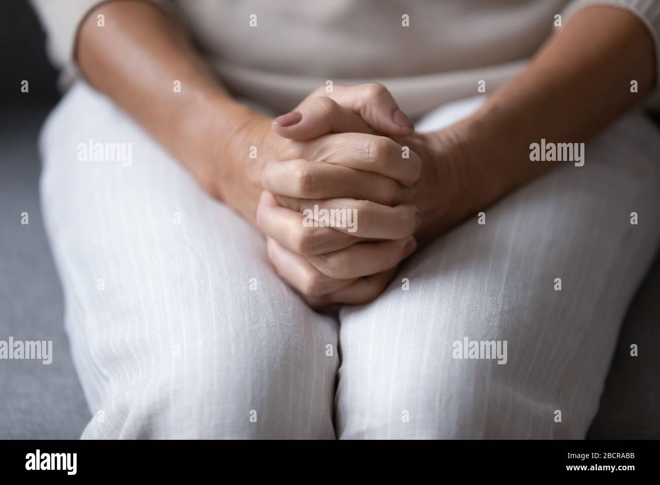 Close up wrinkled female hands clasped together on lap Stock Photo - Alamy