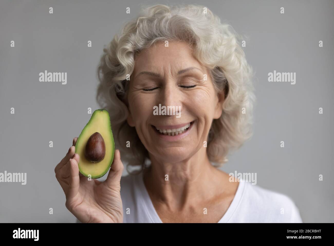 Happy middle aged retired lady holding slice of ripe avocado Stock ...