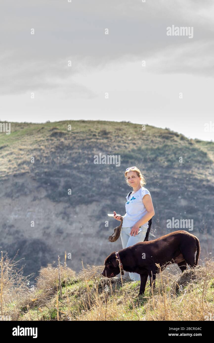 woman outdoors standing with a dog Labrador retriever with Mountain ...