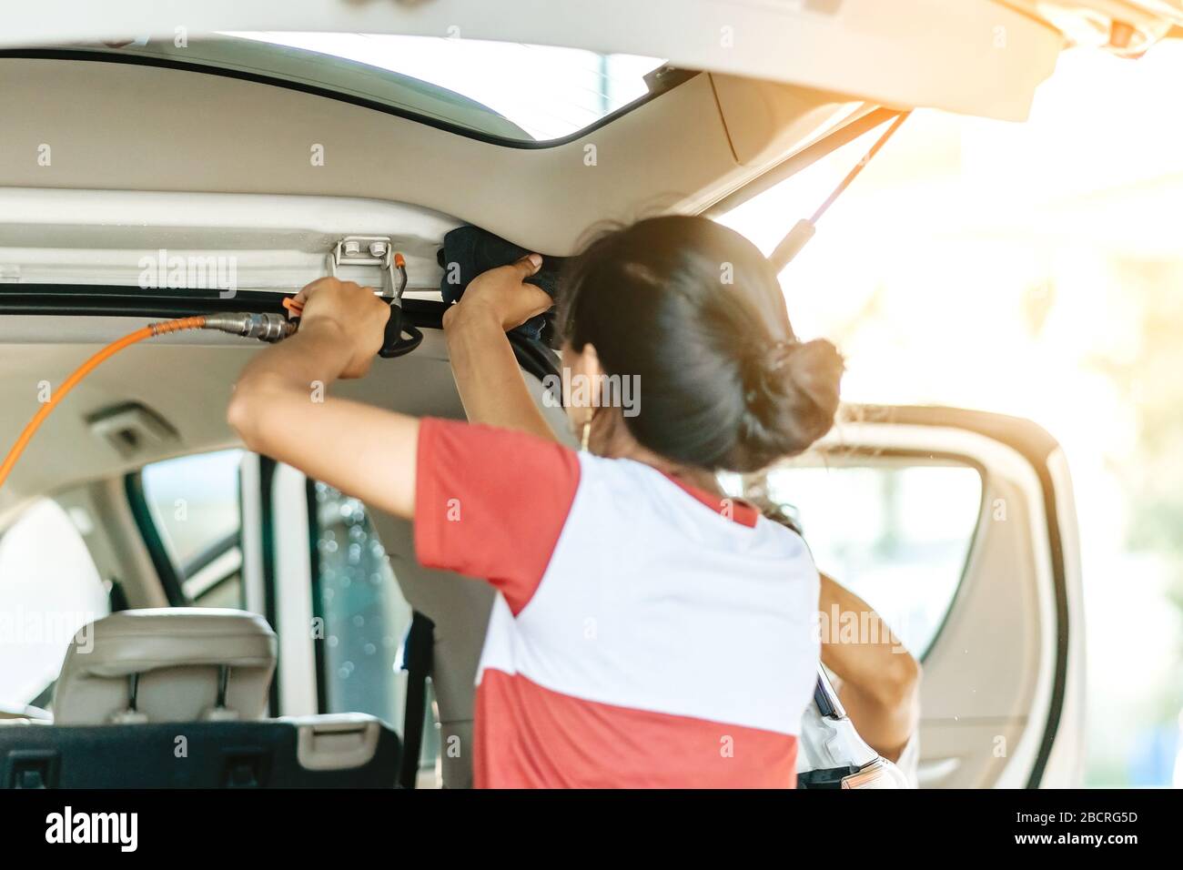 Woman cleaning with a blowers and microfiber wipe the car polishing ...