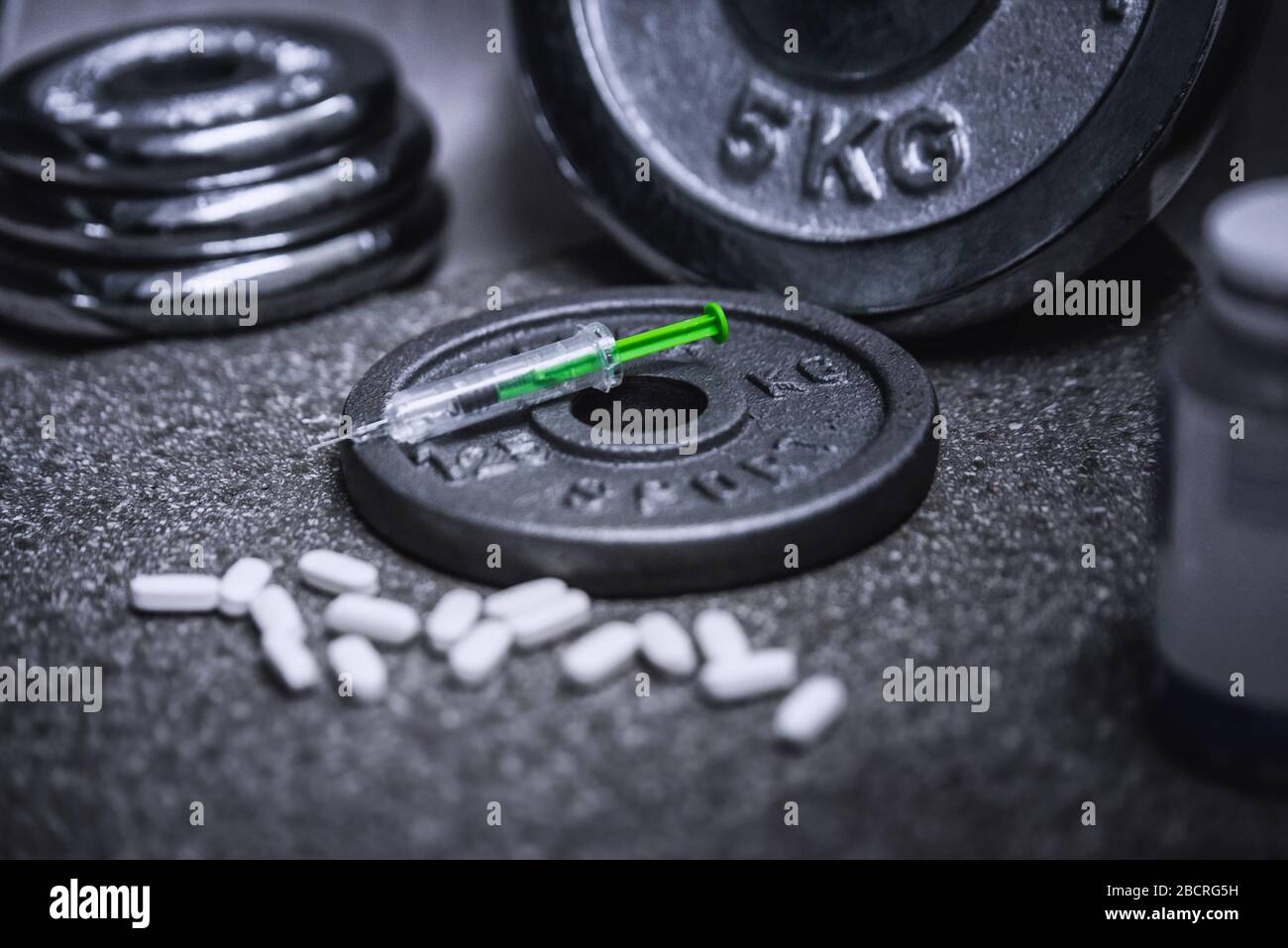 bottle of doping drug and syringe are put in the black ground in gym ...