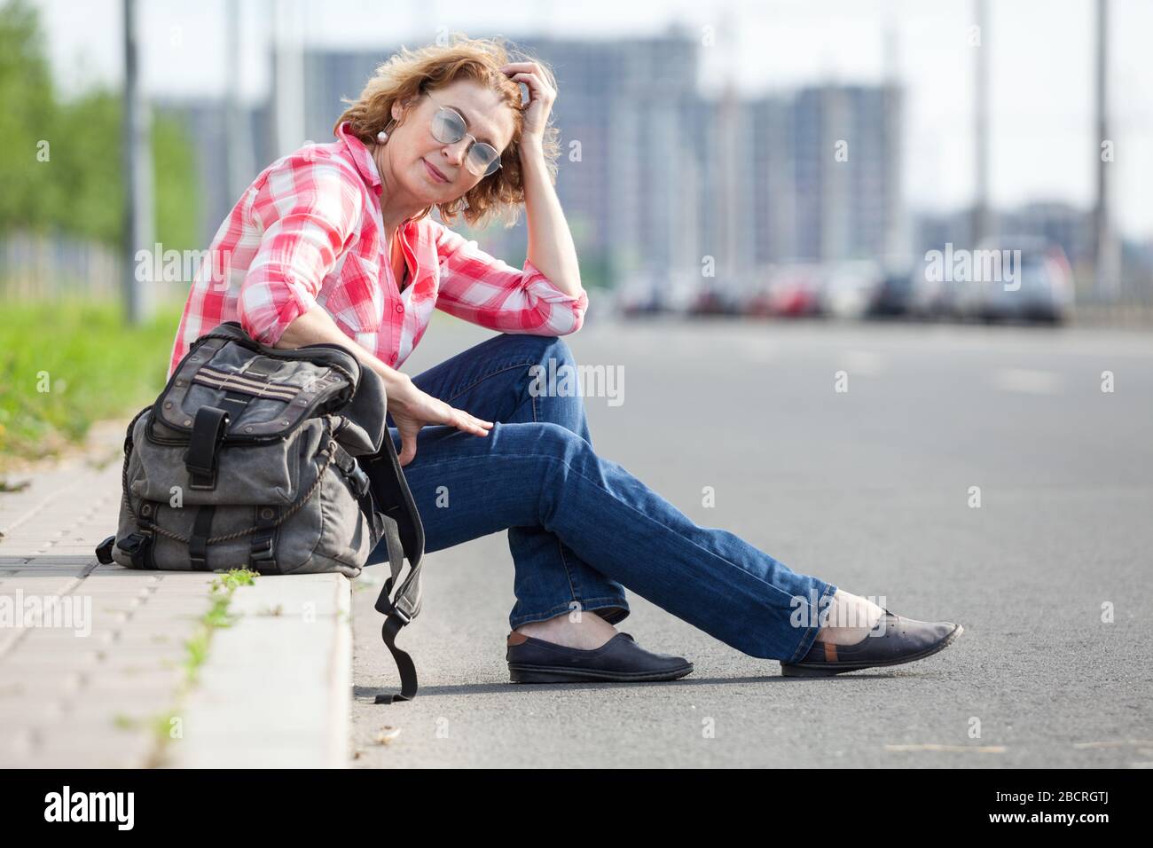 Caucasian woman hitch a ride, alone traveller sitting on roadside and ...