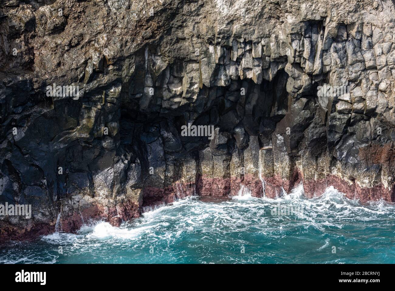 Volcanic rock formation, cliffs of black lava on the rocky shore with ...