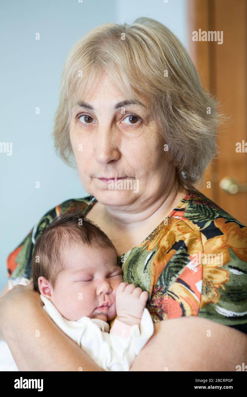 Portrait of mature Caucasian grandmother with newborn sleeping baby in ...