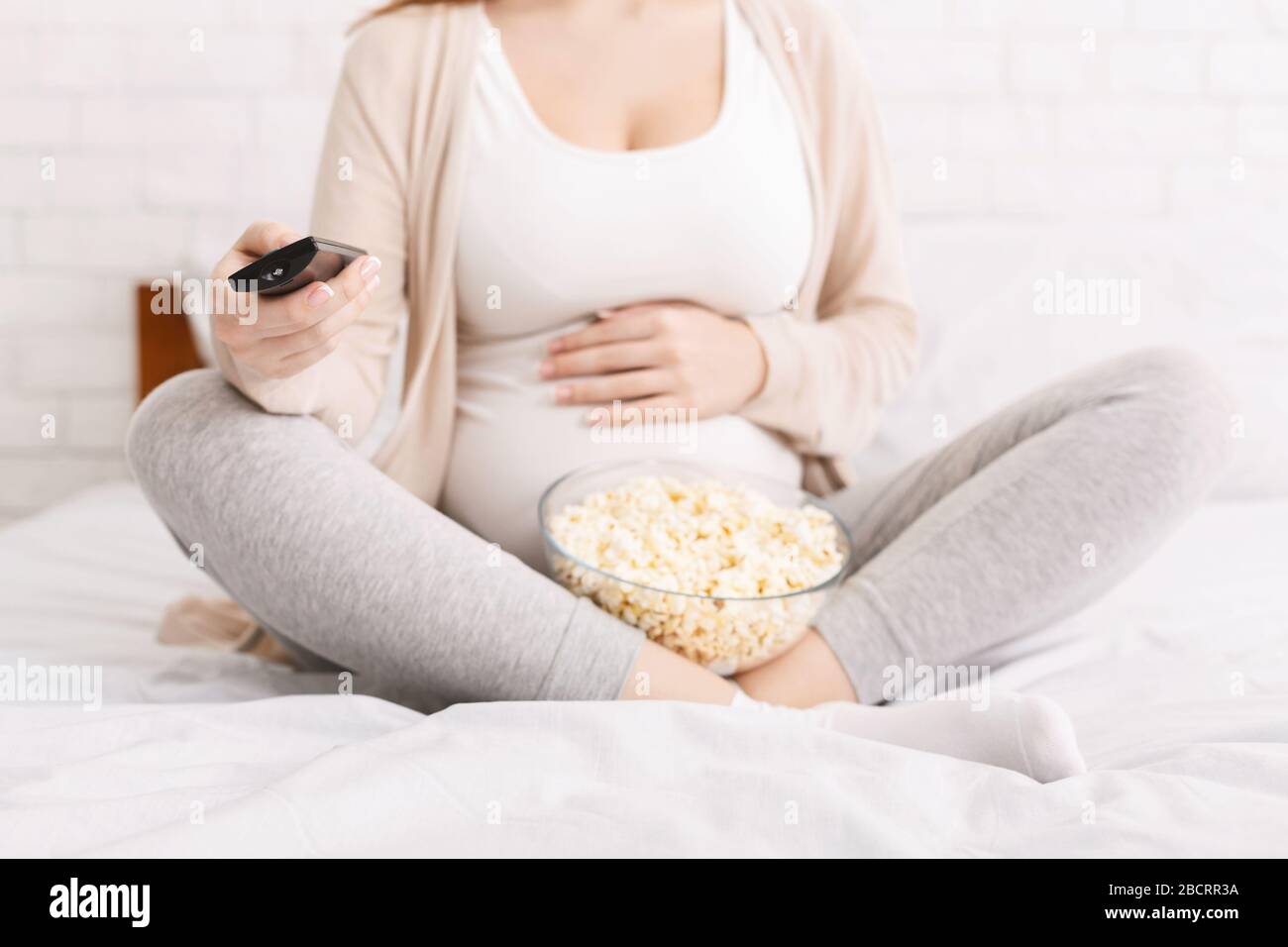 Pregnant woman watching TV and eating popcorn Stock Photo - Alamy