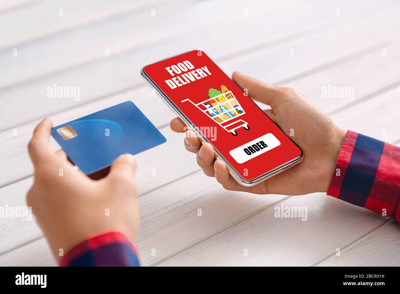 Male hands holding credit card and smartphone with food delivery app ...