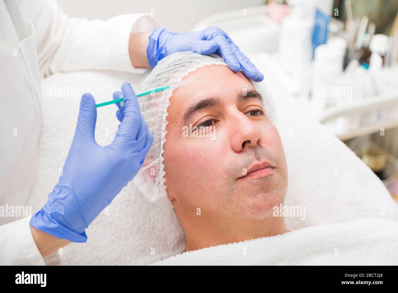 Man receives rejuvenating injection on forehead in medical salon Stock ...
