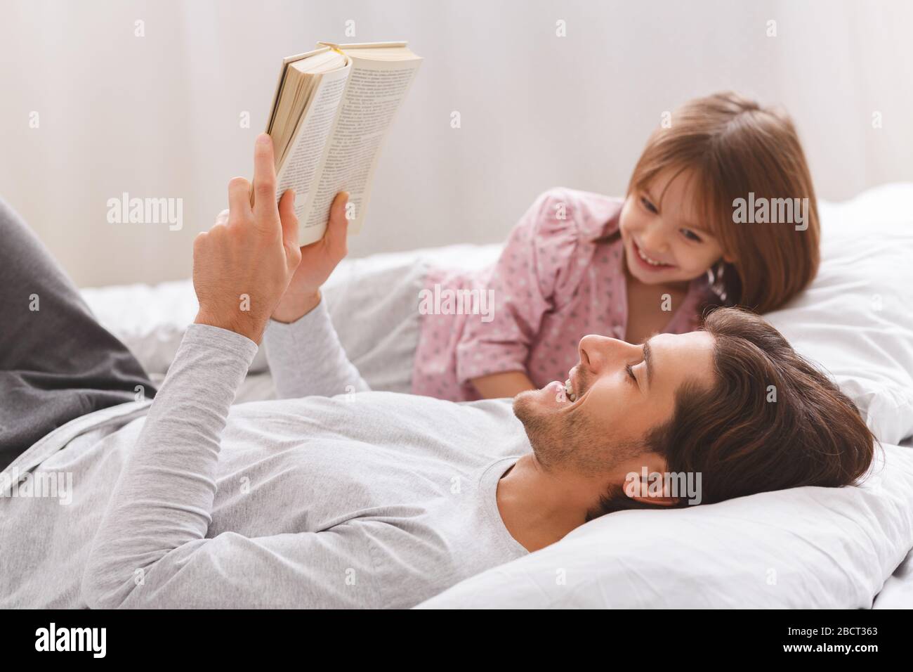 Young father reading book to his little happy daughter Stock Photo - Alamy
