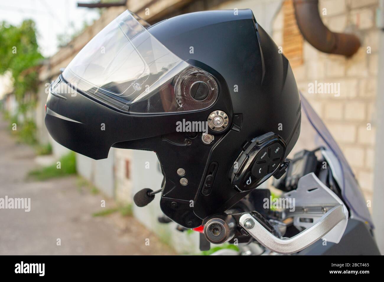 Motorcyclist's crash-helmet hanging on the handle of a motorcycle ...
