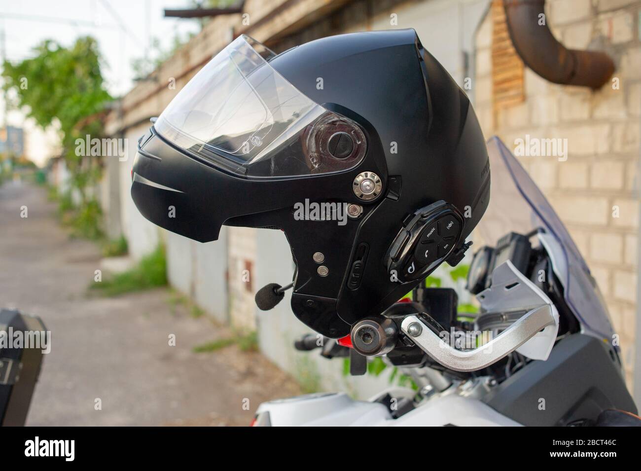 Motorcyclist's crash-helmet hanging on the handle of a motorcycle ...