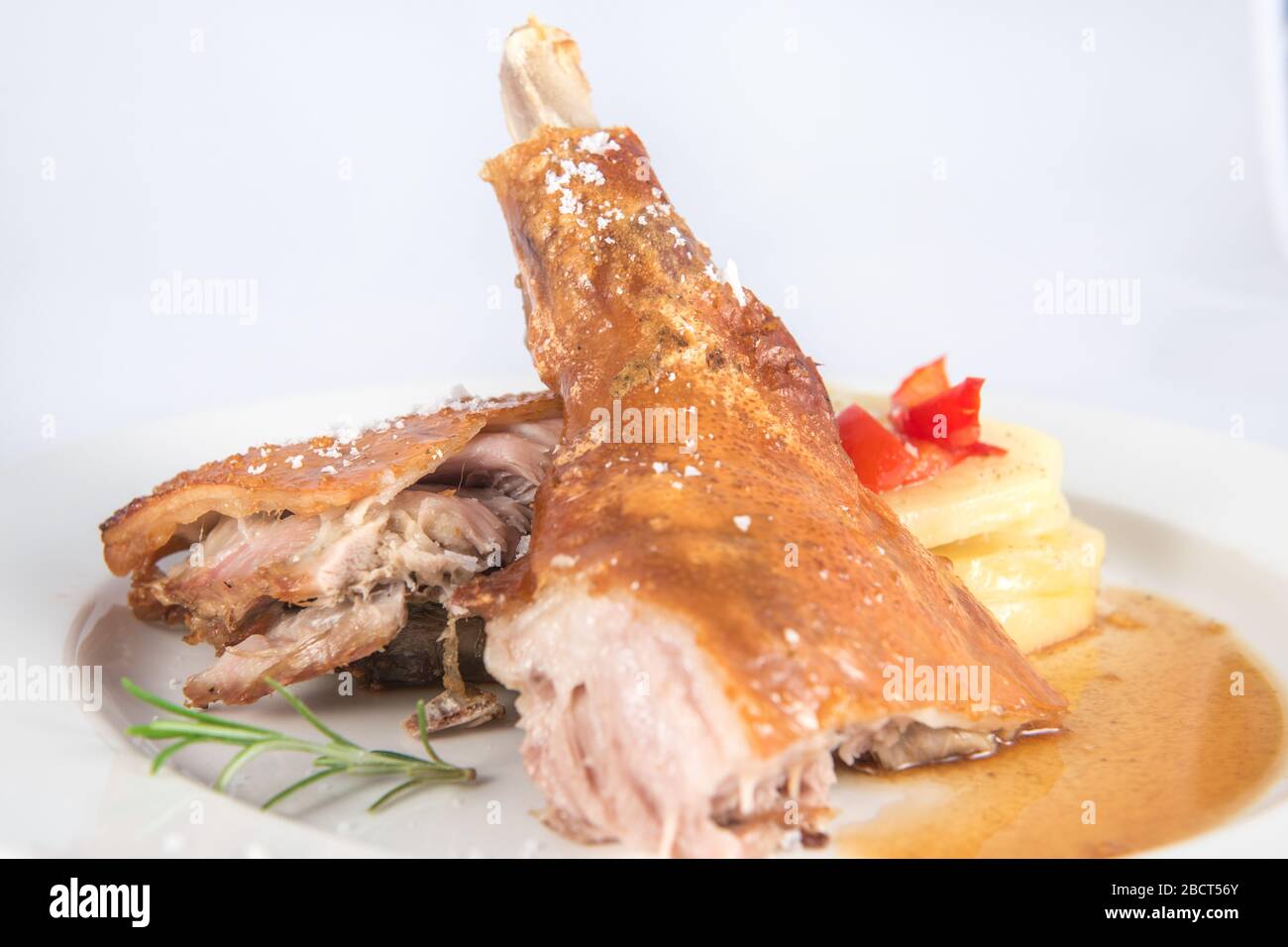Roasted goat's leg with baked potatoes slices Stock Photo - Alamy