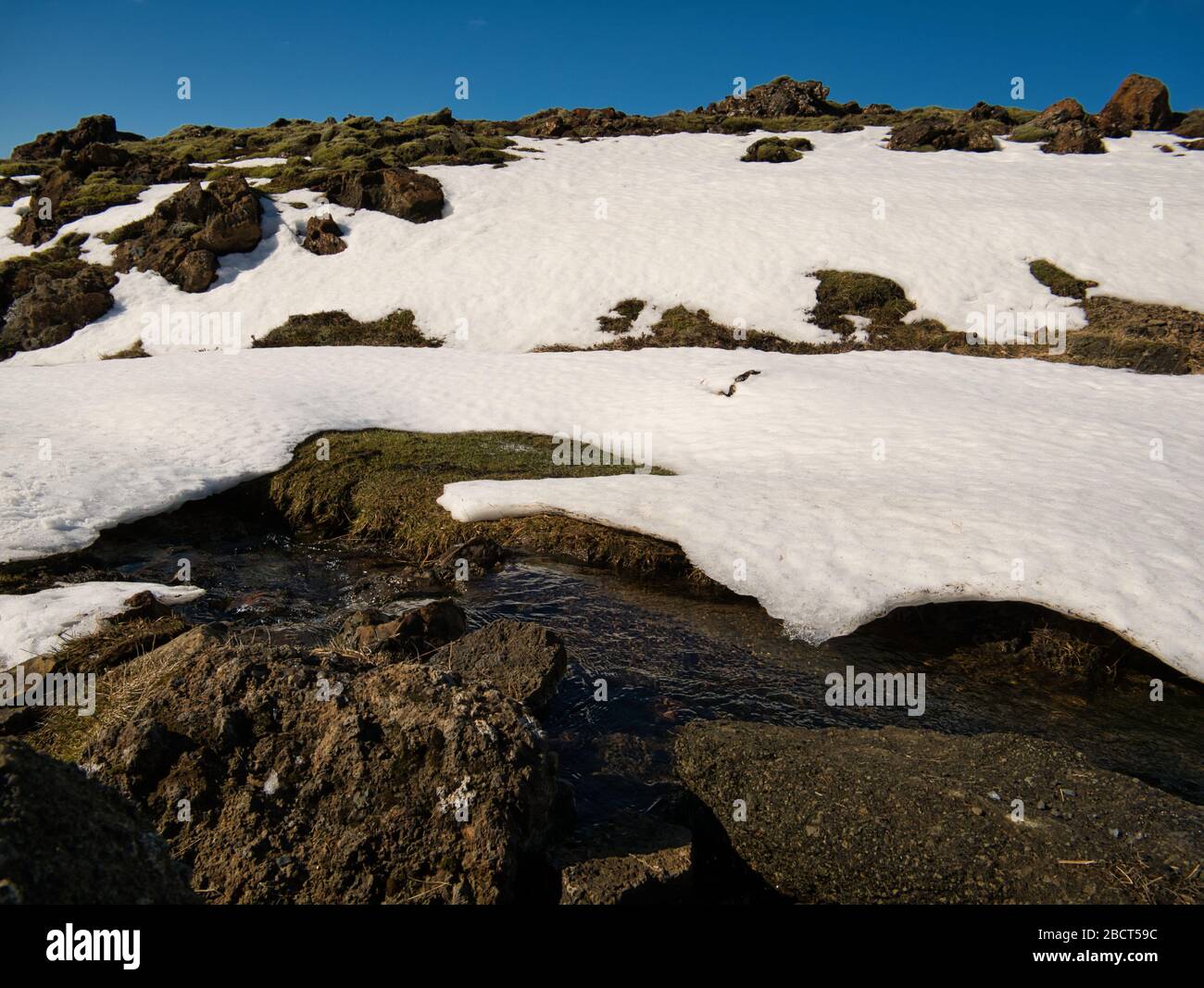 A small mountain stream under a thin layer of snow in spring Stock ...