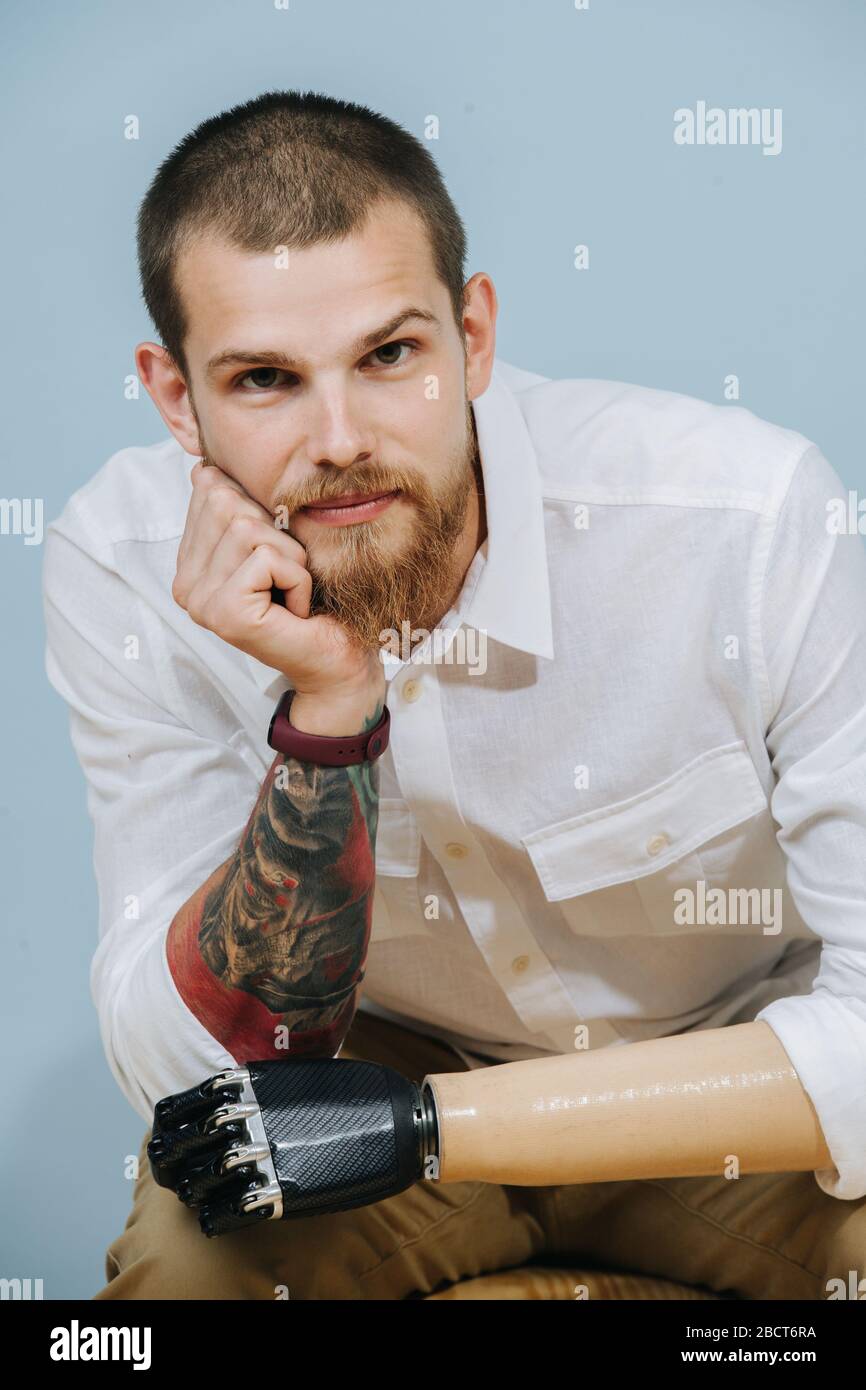 Portrait of a thoughtful man with prosthetic bionic arm over blue ...