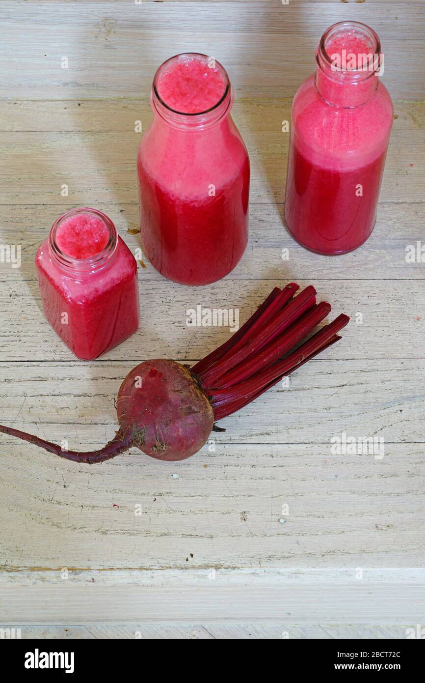 Glass bottles filled with colorful fresh homemade beet smoothies on a ...