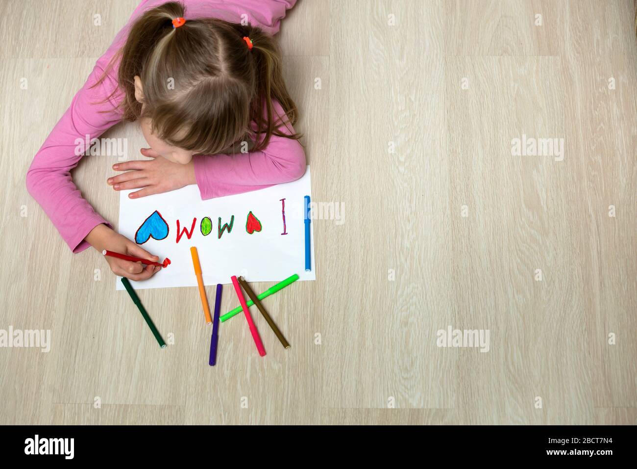 View from above of cute child girl drawing with colorful crayons I love ...