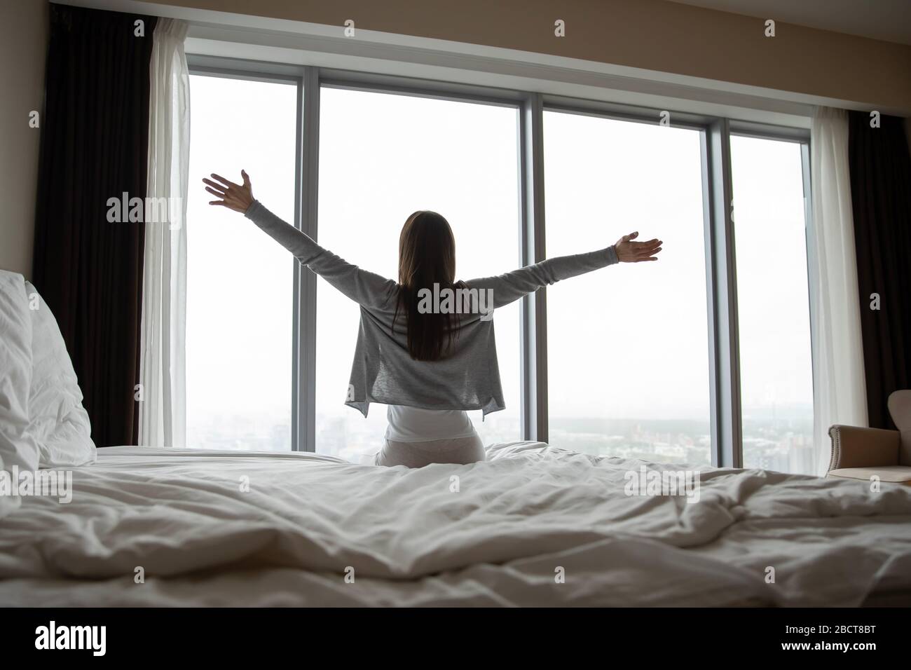 Young woman sit on bed stretching in morning Stock Photo - Alamy