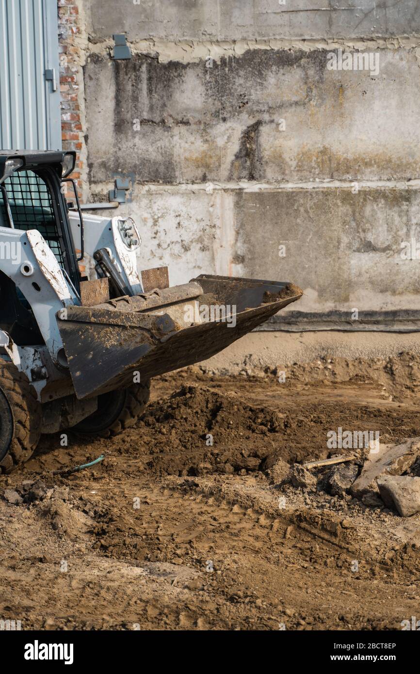 White skid steer loader at a construction site working with a soil ...