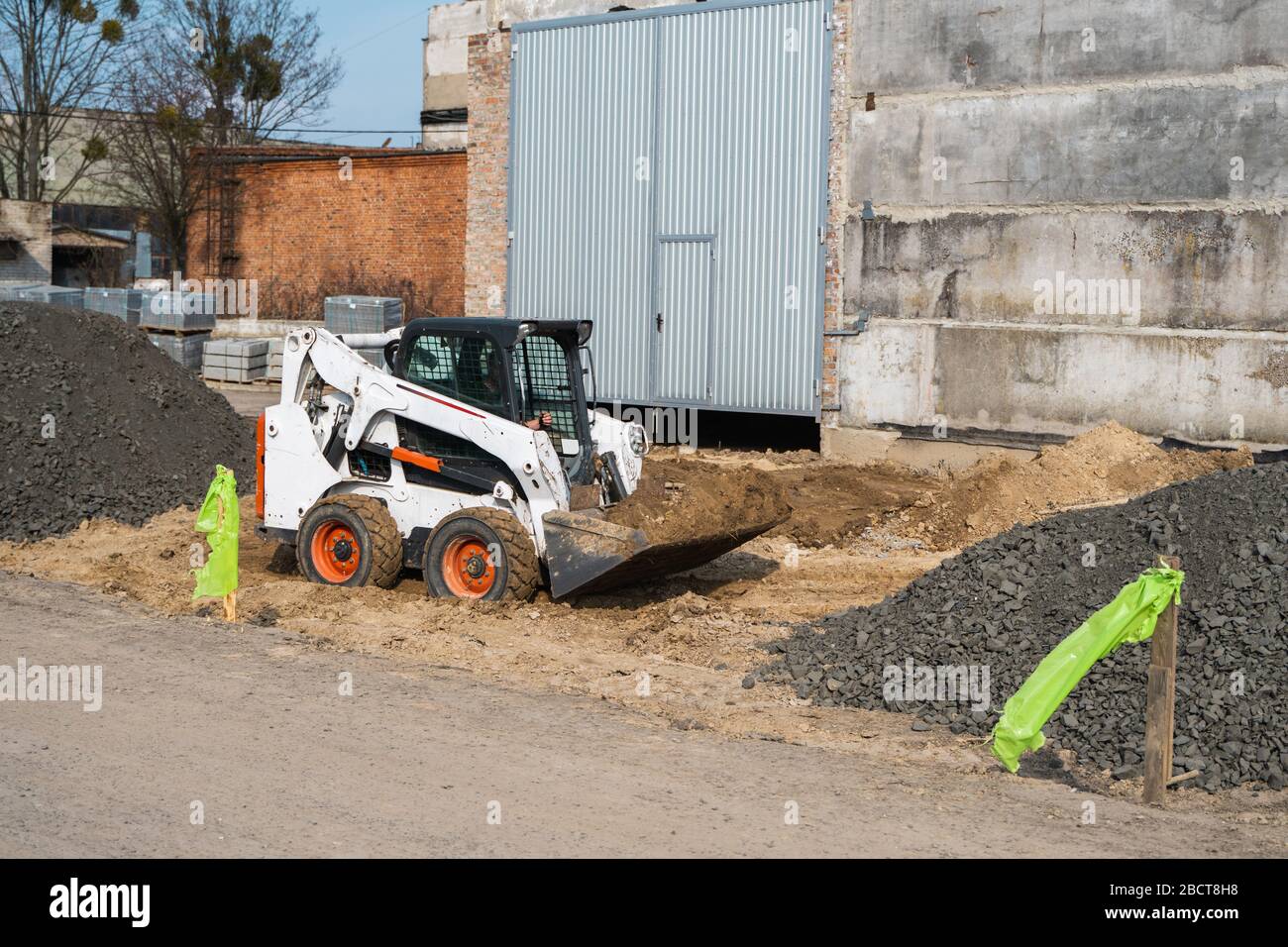 White skid steer loader at a construction site working with a soil ...
