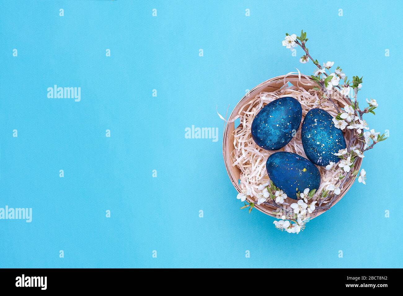 Azure easter eggs in a basket with flowers on a violet background ...