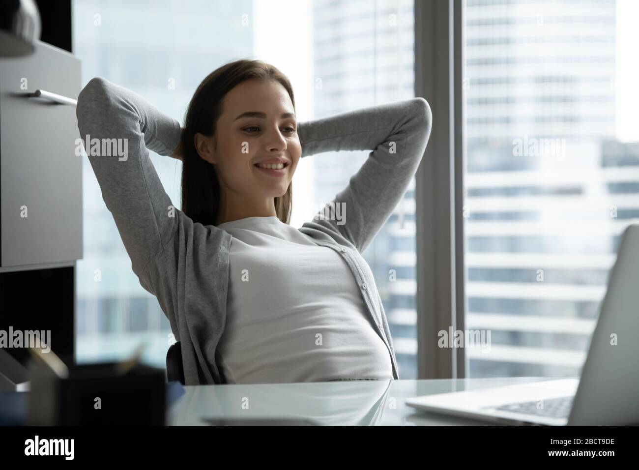 Happy young female employee relax at workplace Stock Photo - Alamy