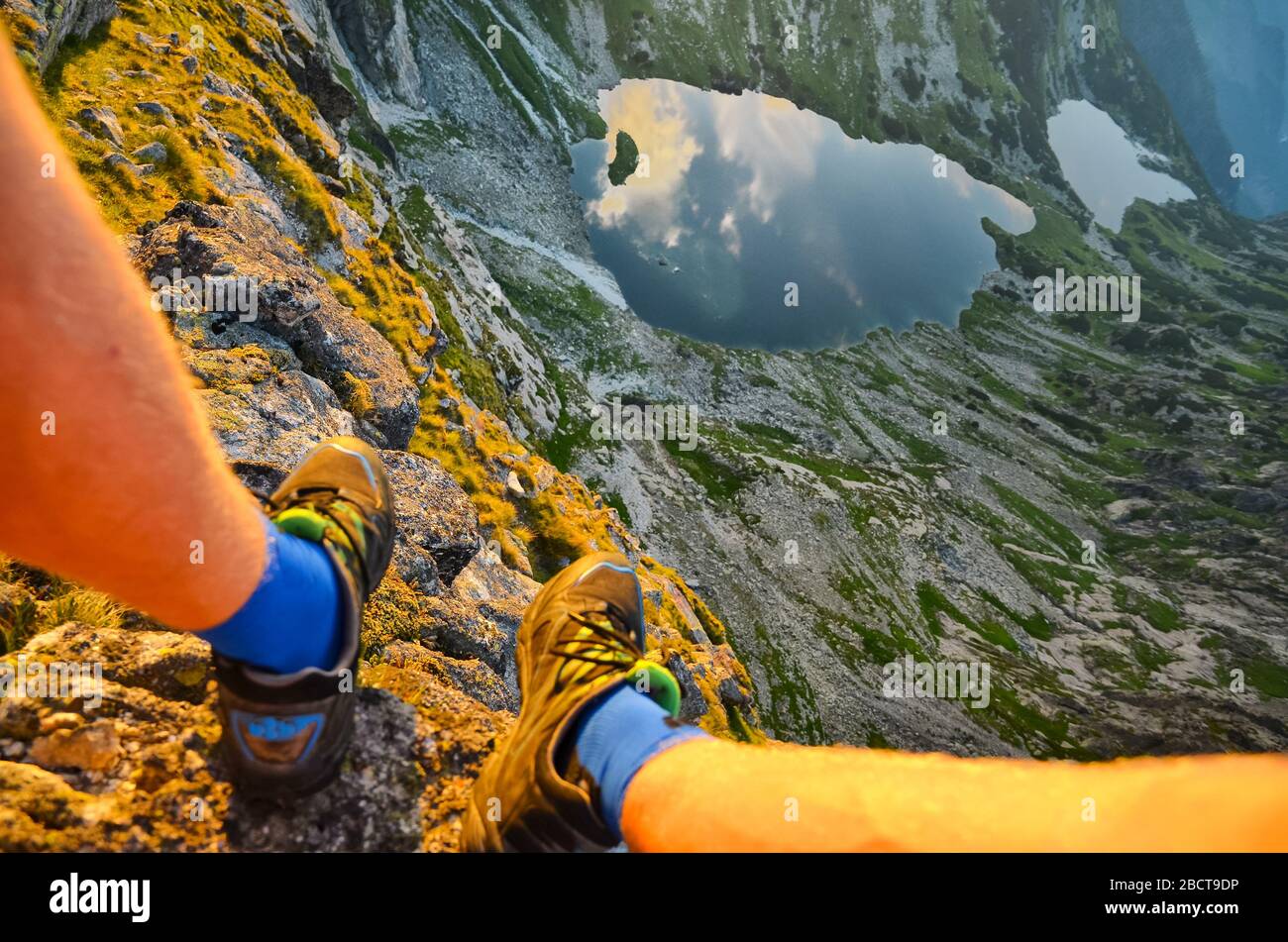Legs of tourist on the top of the hill with two lakes in the valley ...