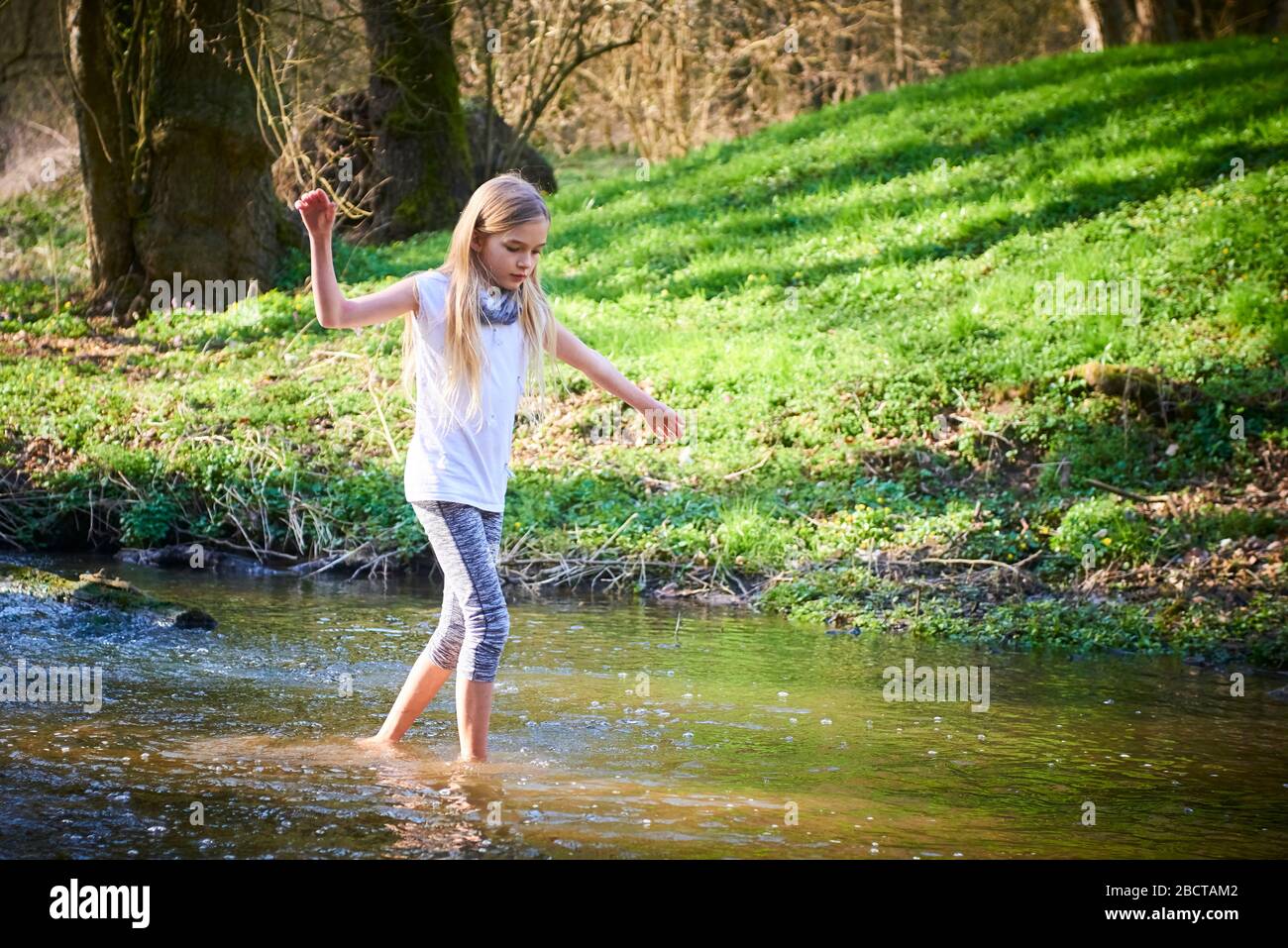 Child cute courageous blond girl playing in the creek. Brave girl ...