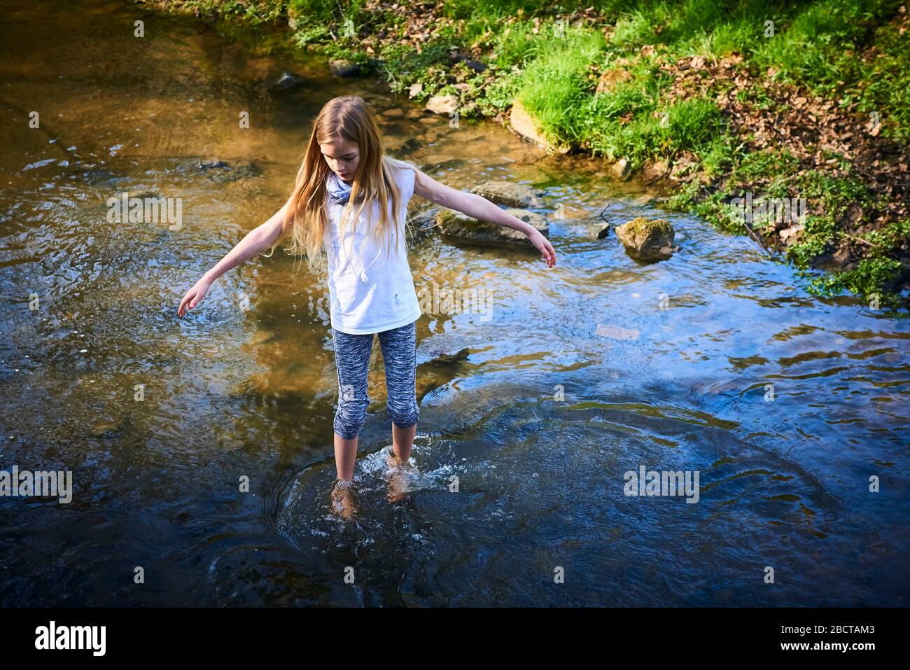 Child cute courageous blond girl playing in the creek. Brave girl ...