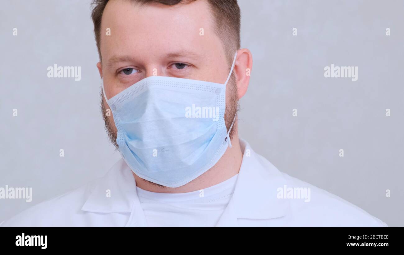 sad and upset Male in a protective mask and a white shirt looks at the ...