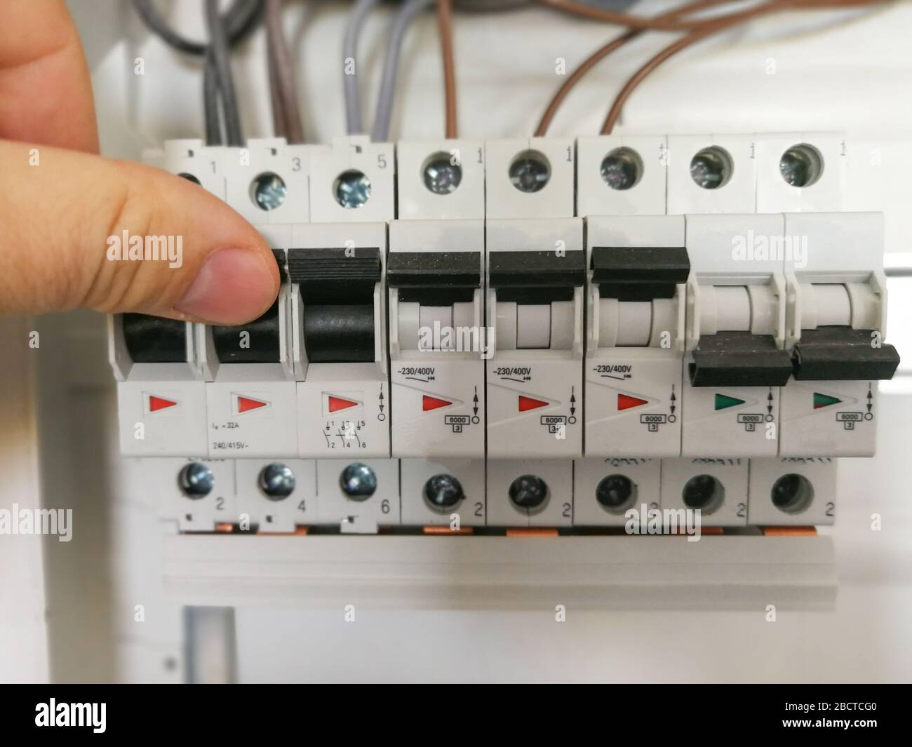 Male finger switching circuit breakers inside electrical panel cabinet ...