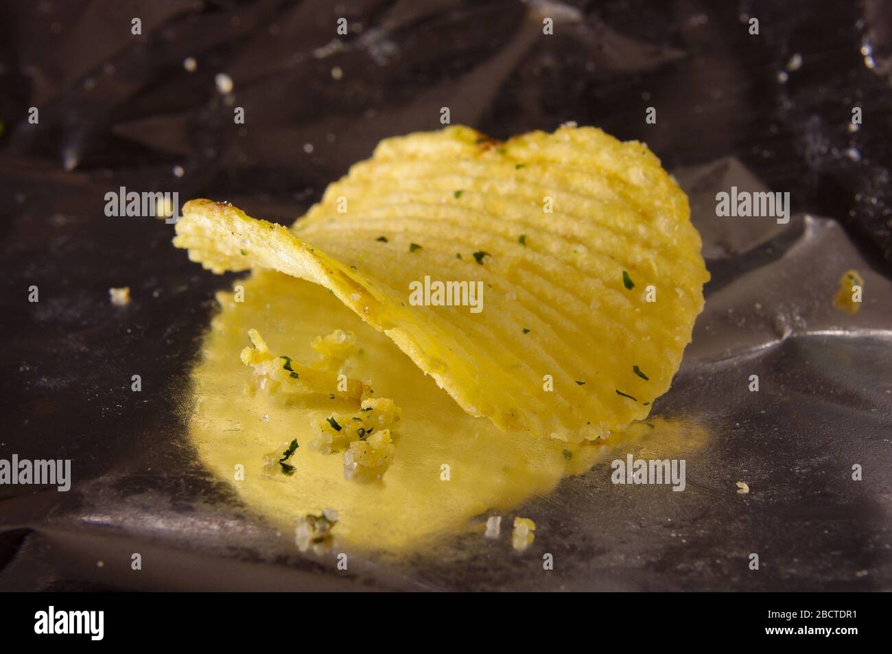 Wavy potato chip isolated on the dark background Stock Photo - Alamy