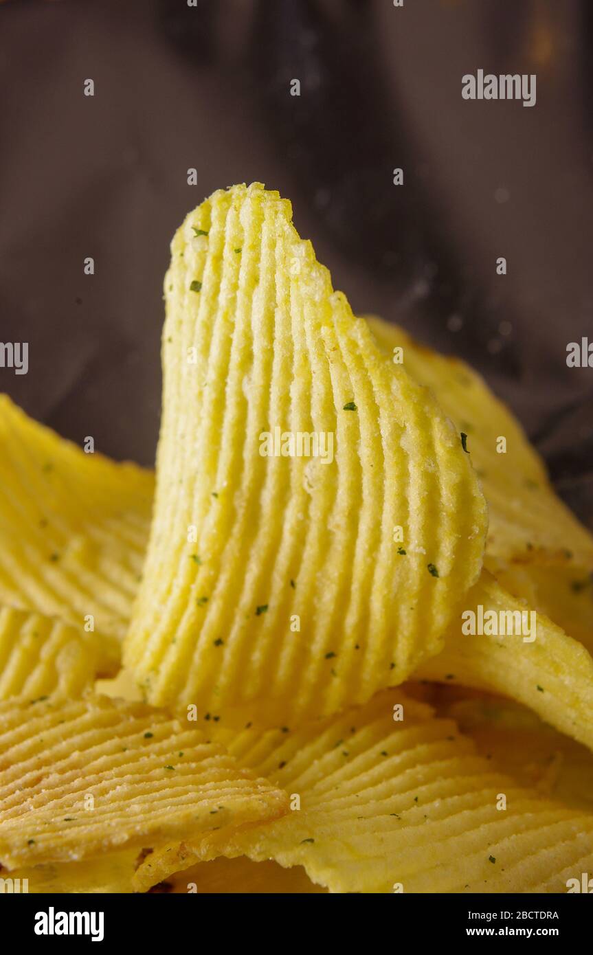 Wavy potato chips isolated on the dark background Stock Photo - Alamy