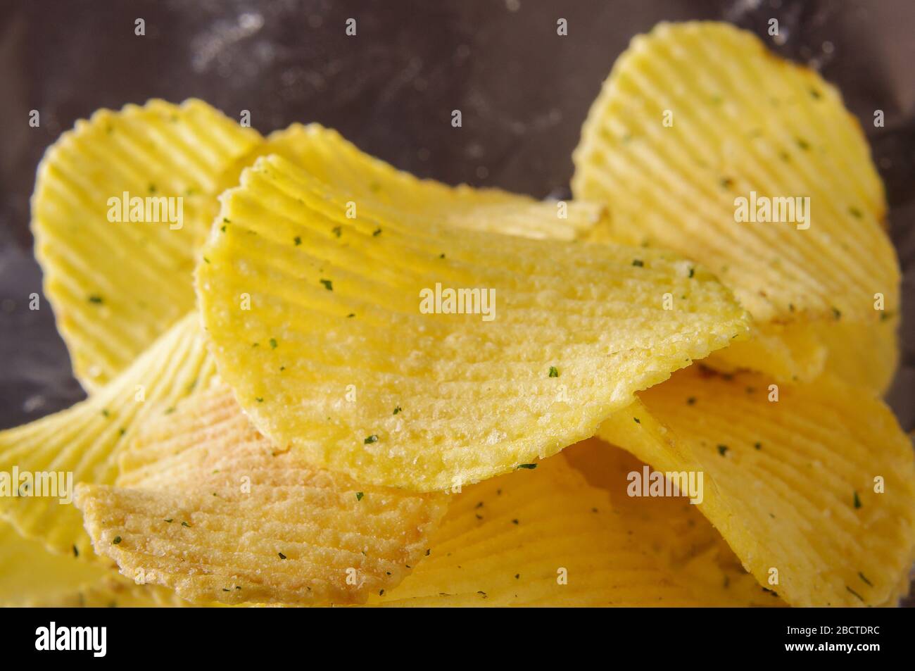 Wavy potato chips isolated on the dark background Stock Photo - Alamy