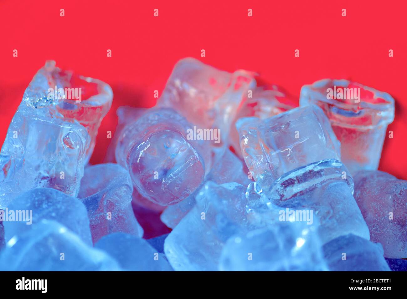 many pieces of ice of different shapes. ice lie on a red background ...