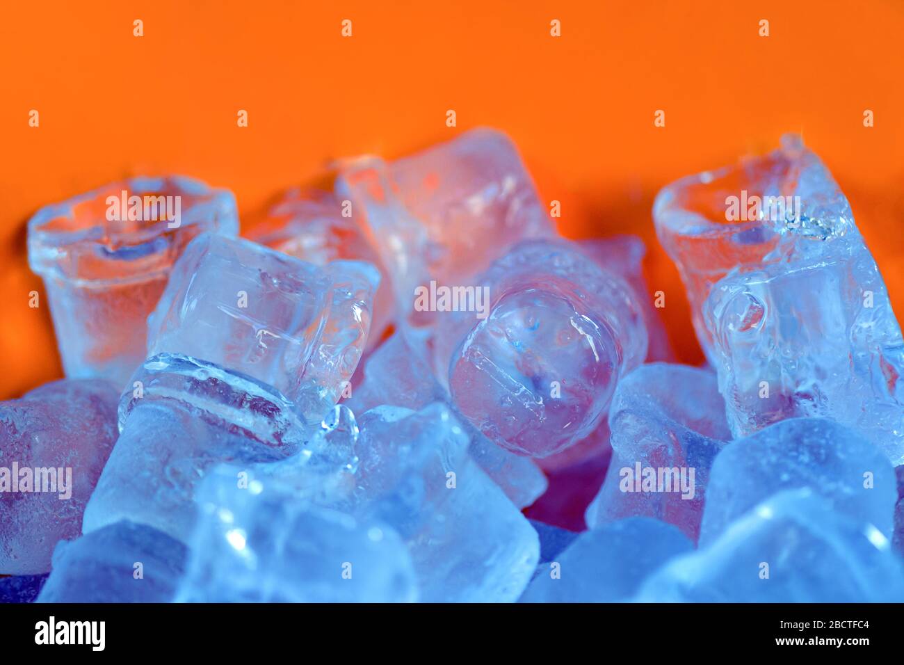 many pieces of ice of different shapes lie on an orange background. ice ...