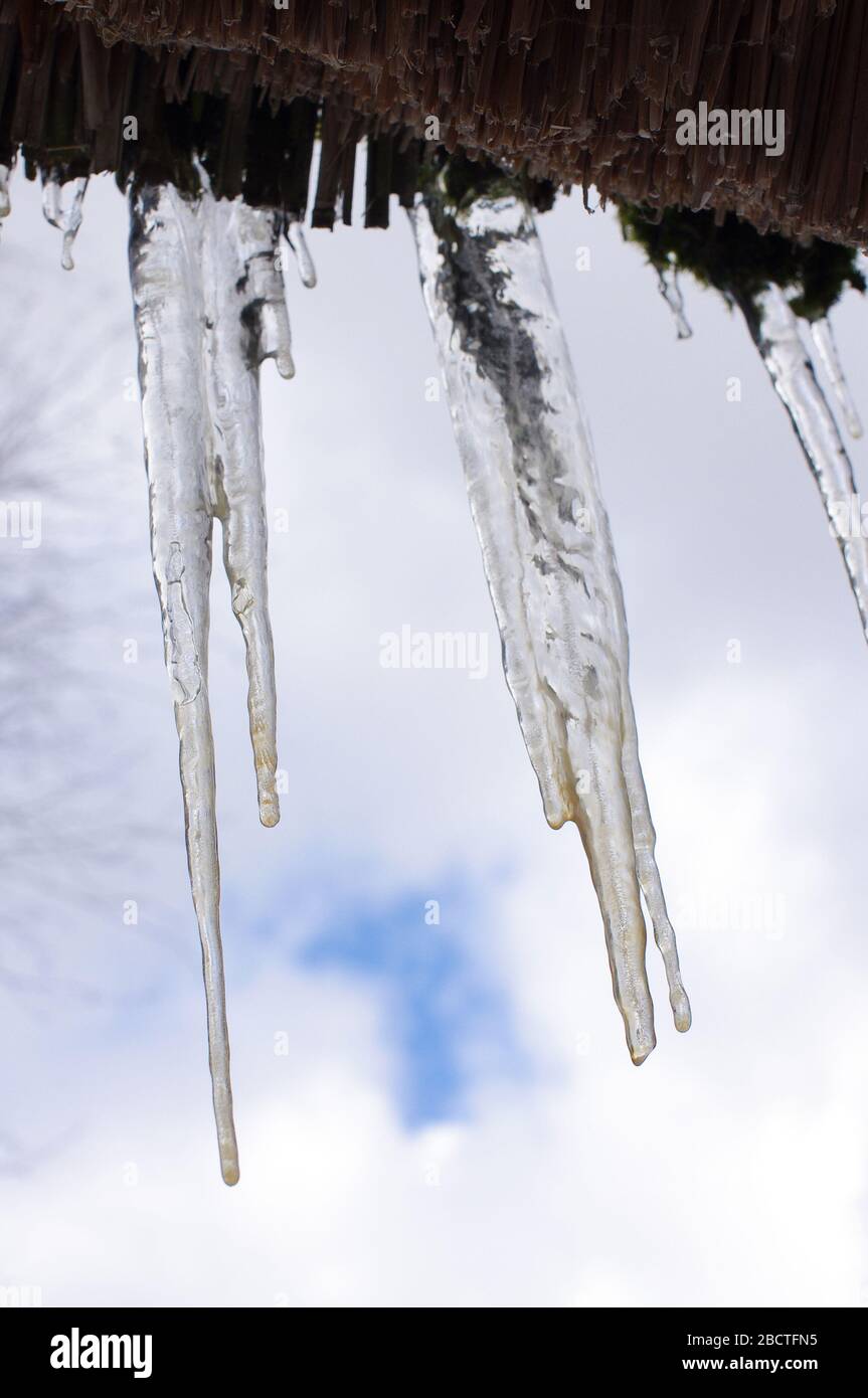 Long icicles on the roof of the house during spring time Stock Photo ...