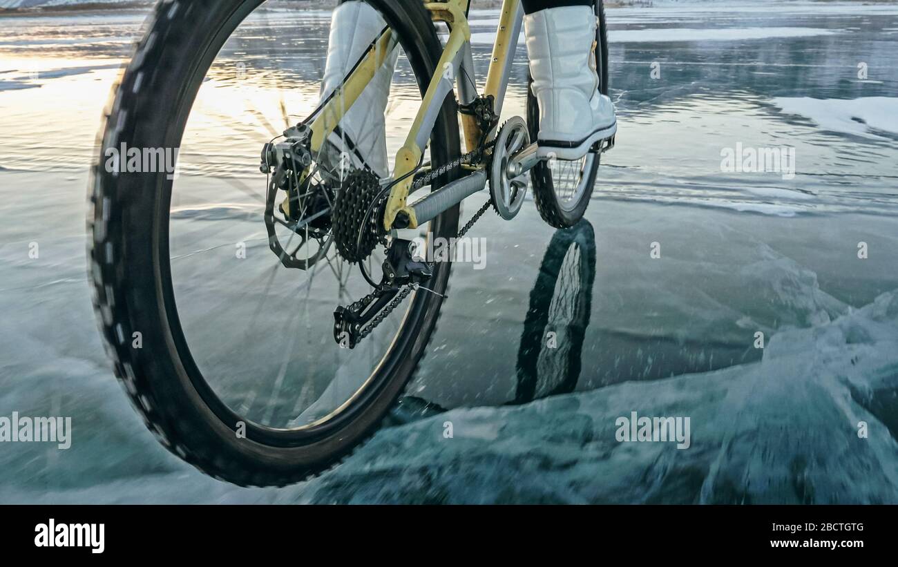 Woman is riding bicycle on the ice. Tires on bike are covered wi Stock ...