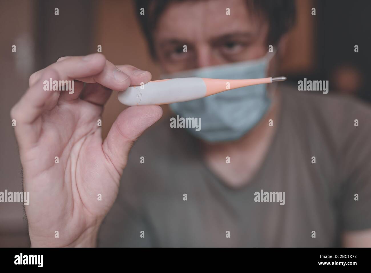 Man in self-isolation measuring body temperature electronic digital ...