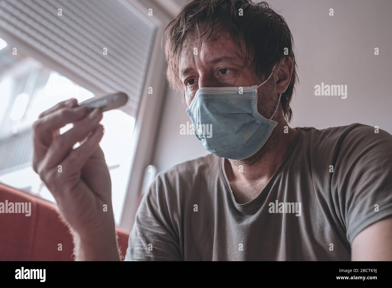 Man in self-isolation measuring body temperature electronic digital ...