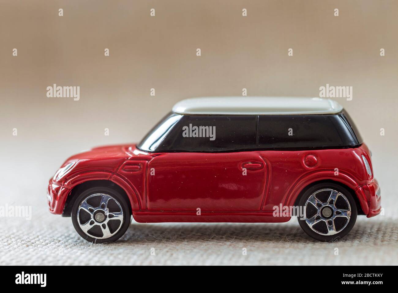 Small bright red metal simple child toy car with dark windows on light ...