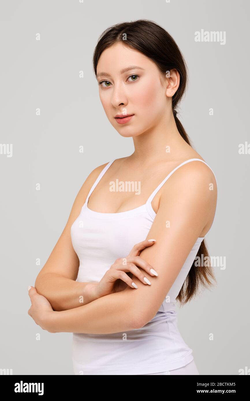 Portrait of beautiful happy asian girl with arms folded on the stomach ...