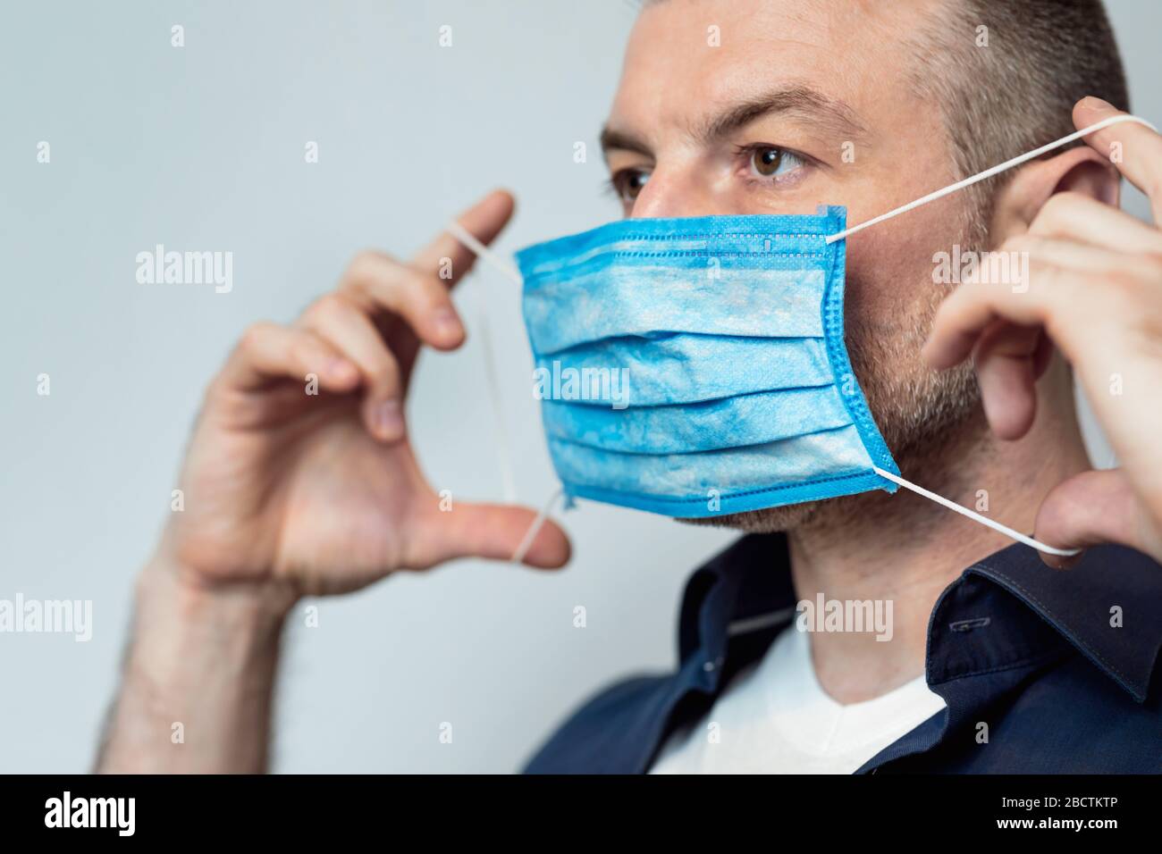 Man Putting On Medical Mask Standing Over Gray Studio Background Stock ...