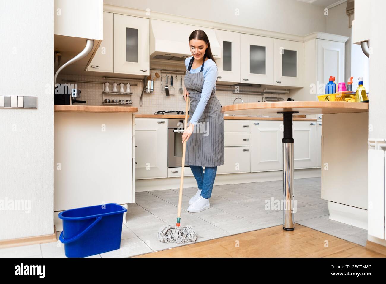 Young woman using mop to clean floor Stock Photo - Alamy