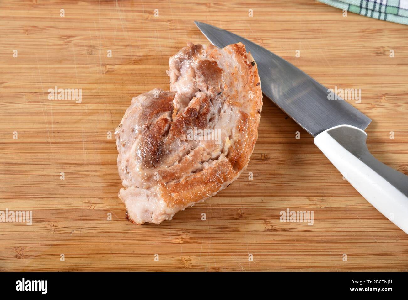 Overhead view of a slab of juicy roasted pork belly on a cutting board ...
