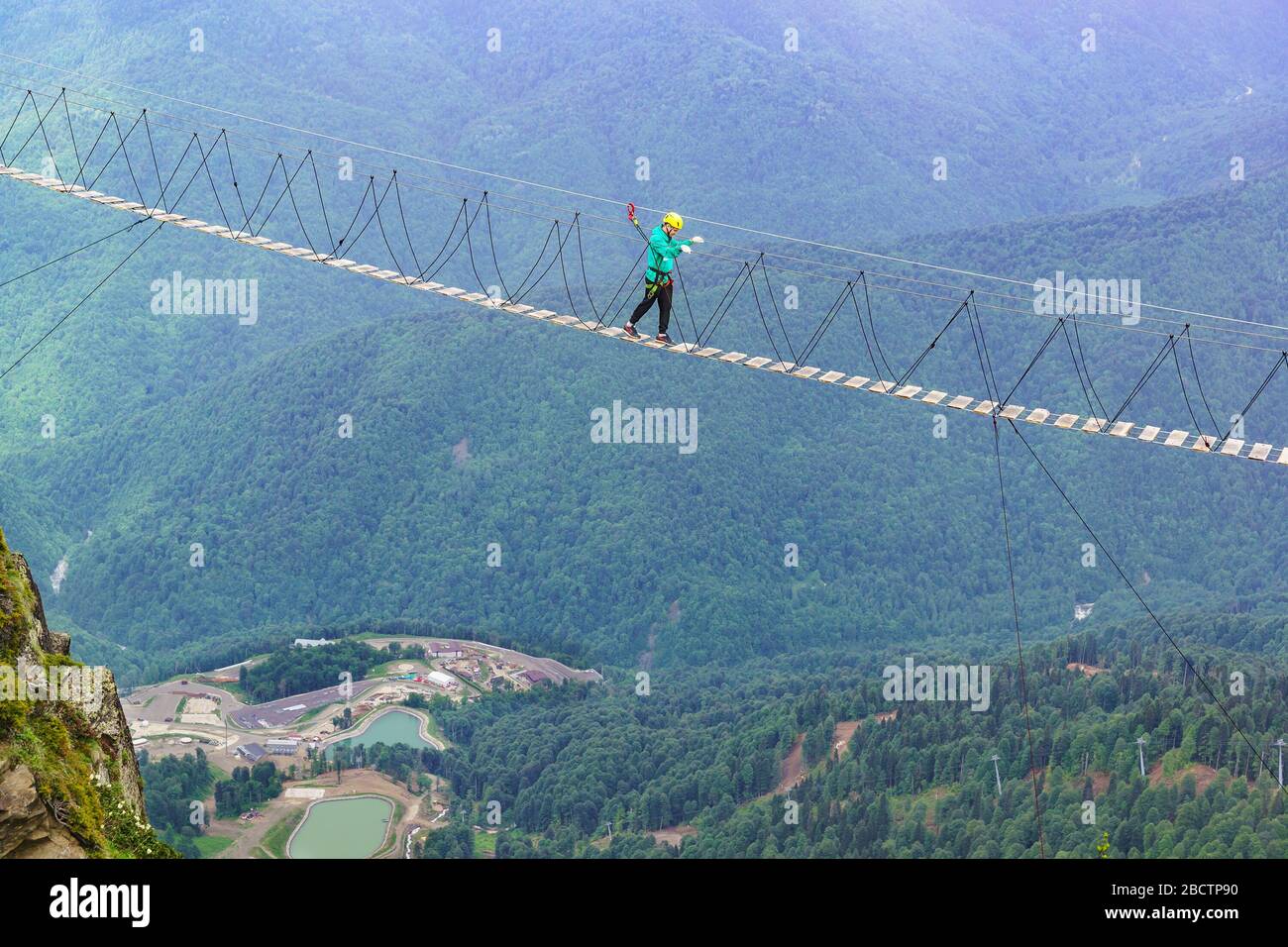 A tourist in a helmet and safety ropes is at the stretched over the ...