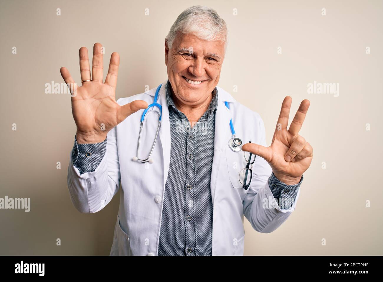 Senior handsome hoary doctor man wearing coat and stethoscope over ...