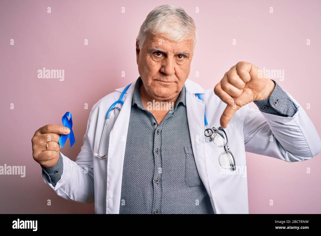 Senior handsome hoary doctor man wearing stethoscope holding blue ...
